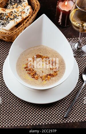 Appetizing green cream soup in dark bowl on marble countertop ...