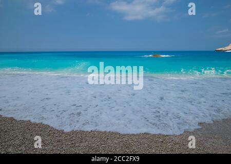 Foam covering the pebbles after big wave crushed on the beach with ...