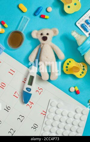 Pills, spoon of syrup, electronic thermometer near calendar page Stock ...