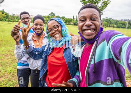 Group of cheerful African friends with facemasks having a drink and ...