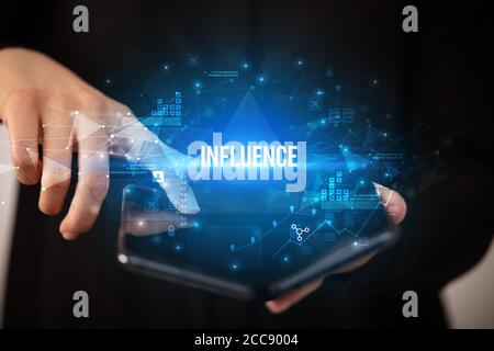 Businessman holding a foldable smartphone with INFLUENCE inscription ...