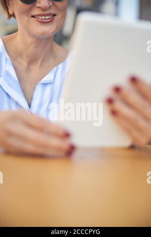pleased woman in sunglasses and trendy outfit holding handbag while ...
