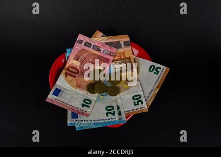 euro notes and coins on a saucer with heart Stock Photo - Alamy
