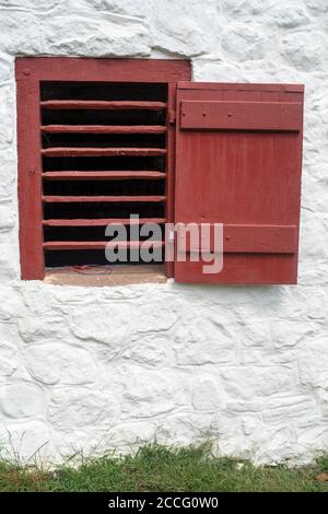 A vertical shot of a wooden barn with a red roof on a forest background ...