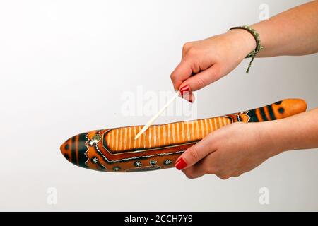 Highly decorated Gourd Guiro being played with a feather quill scraper ...