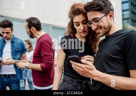 Young friends hanging out, using smart phones in sunny city Stock Photo ...