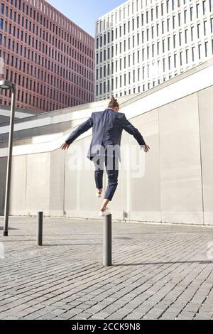 Balancing businessman . Rear view Stock Photo - Alamy