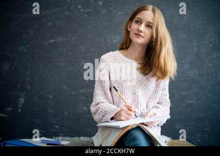 Black girl writing in exercise book while doing homework with her ...