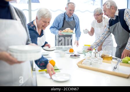 Group of seniors laying table for coffee party in retirement home Stock ...
