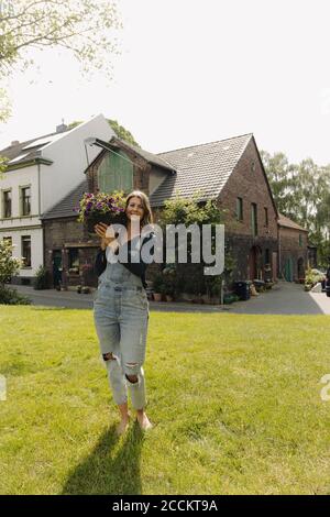 Happy woman farmer carrying box with fresh growing tulips working at ...