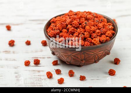 Dried Rowan berries in a ceramic bowl on a white table. Selective focus ...