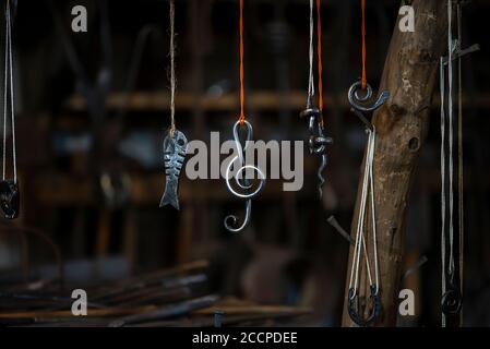 Blacksmith decorative elements hanging at forge, workshop. Handmade ...