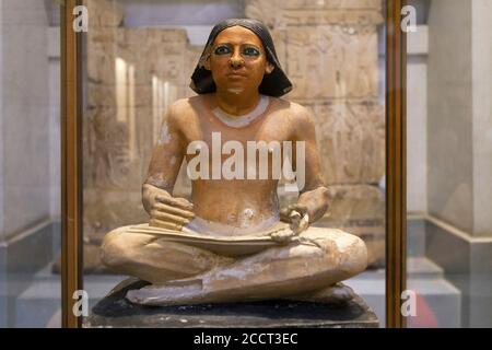 painted limestone statue of an Egyptian scribe seated cross-legged ...