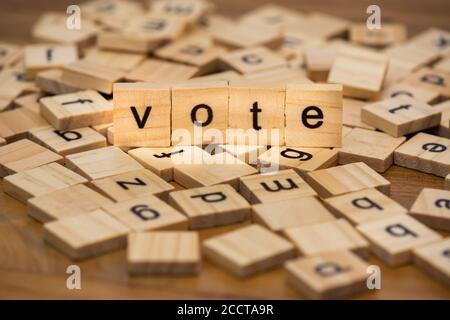 Wooden letters composing the word "vote" on a background of scattered ...