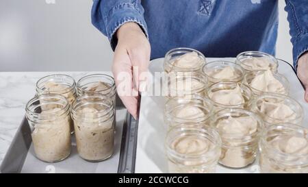 Step by step. Scooping homemade chocolate ice cream into glass jars ...