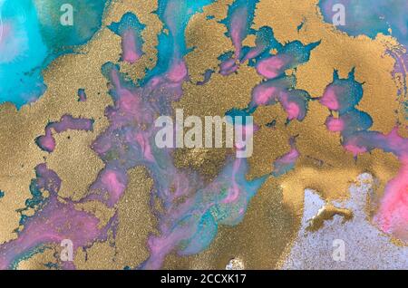 Pink, gold and green mixed inks spilled on white paper background ...