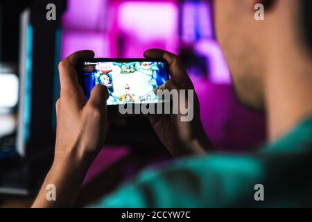 Image closeup of focused man playing video game on mobile phone and ...