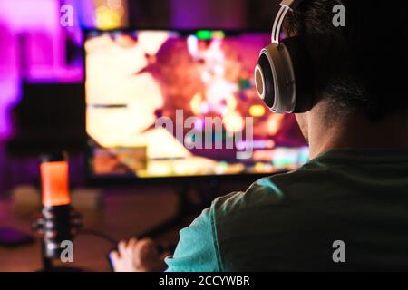 Image of focused man in headphones playing video game on computer while ...