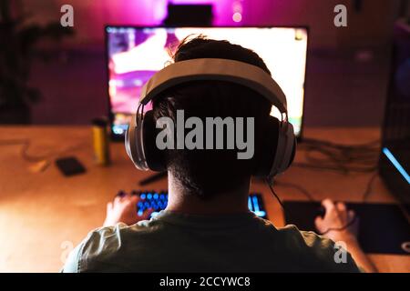 Image of focused man in headphones playing video game on computer while ...
