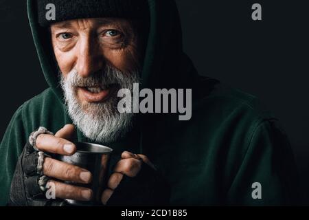 Old grey-bearded frozen tramp man with grey beard embracing himself to ...