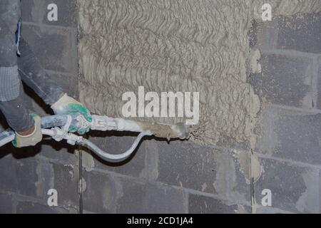 Machine application of plaster to the wall. Plasterer spraying plaster ...
