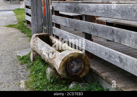 Water trough made out of tree trunk in the alps Stock Photo - Alamy