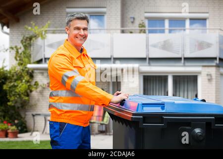 Waste collector holding a garbage bin and a broom isolated on white ...