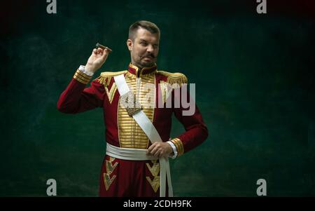 Disguasted smoking cigarette. Young man in suit as Nicholas II on dark ...
