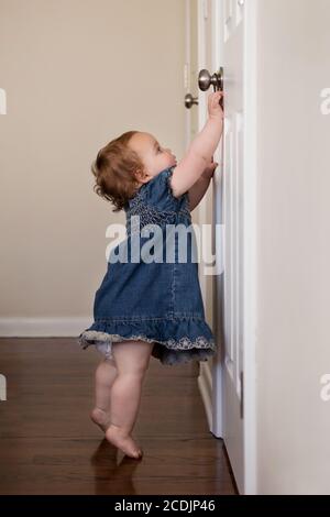 Baby trying to reach door knob. Child on tip toes reaching for door2 ...