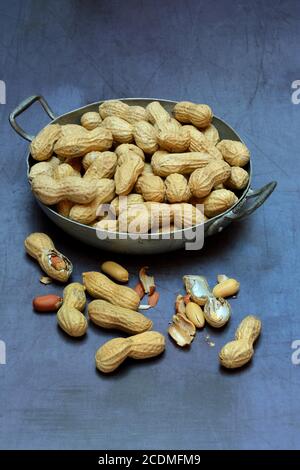 Small bowl with peanuts in the shell on wooden background, top view ...