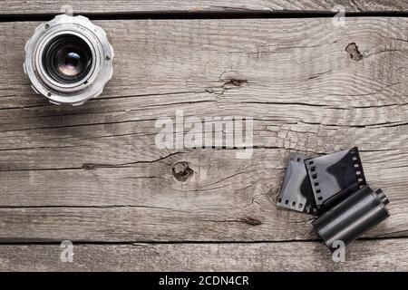 retro camera, negative film, lenses and old paper frame on wooden table ...
