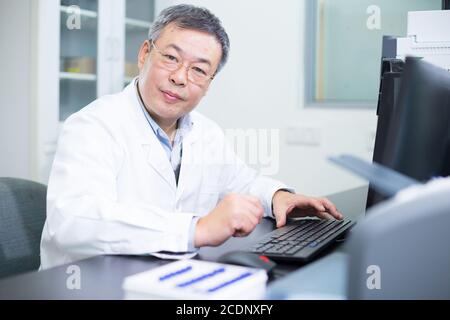 Asian old man analysises experimental data in lab Stock Photo - Alamy