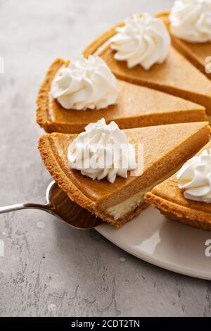 Slices of pumpkin pie with whipped cream on top served on rustic wooden ...
