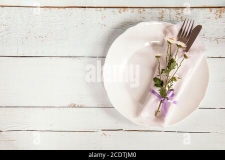 Plate and cutlery tied with pink ribbon on light table. Valentine's Day ...