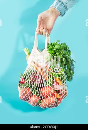 Woman hold mesh bag with vegetables and herbs. Modern reusable shopping ...