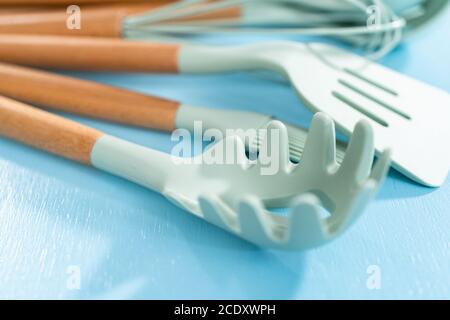 New blue silicone kitchen utensils with wooden handles on a blue ...