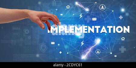 Hand pointing at IMPLEMENTATION inscription, modern technology concept ...