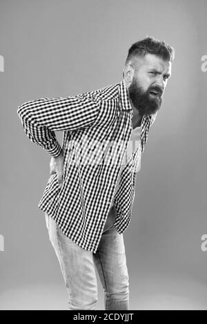 Bent over feeling sharp pain in back. Bearded man suffer from pain ...