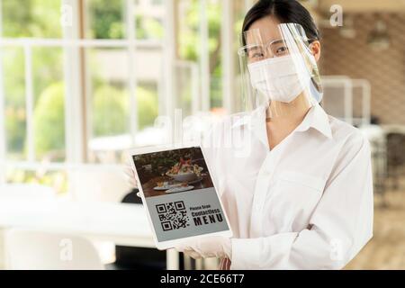 New Normal asian waitress hold qr code contactless menu tablet Stock Photo - Alamy