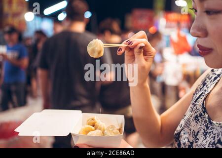 Side view of ethnic female with takeaway hot drink looking at camera ...