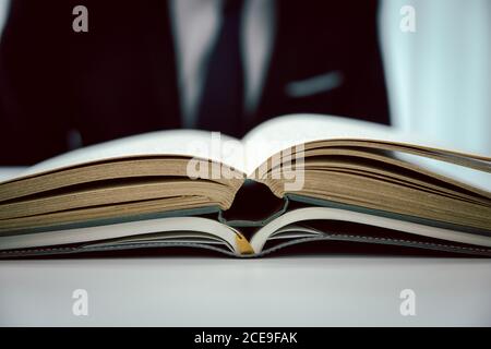 Thick book opened on desk in bookshop, a man in the background Stock ...