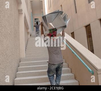 Man carrying metal object above his shoulder walking in the stairway ...