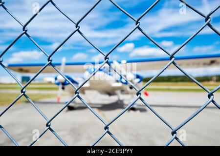 Airplane on runway behind wire mesh fence Stock Photo - Alamy