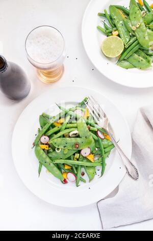 Green pea pods and fork on the white plate Stock Photo - Alamy