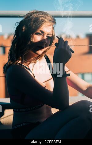 A vertical portrait of a young caucasian smoking female with colored ...
