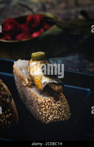 Tasty breads with canned fish and olives lying on baking pan near hot ...