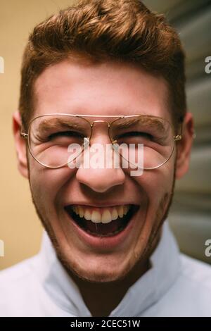 Cheerful and funny redhead man with beard, wearing glasses, laughing ...