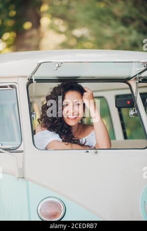 Woman sitting in a car, smiling while holding a smartphone and reusable ...
