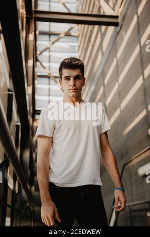Young handsome man thinking and looking down against gray Stock Photo ...