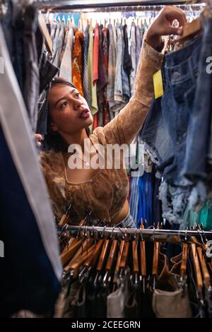 Focused casual young female searching info on smartphone near packed ...